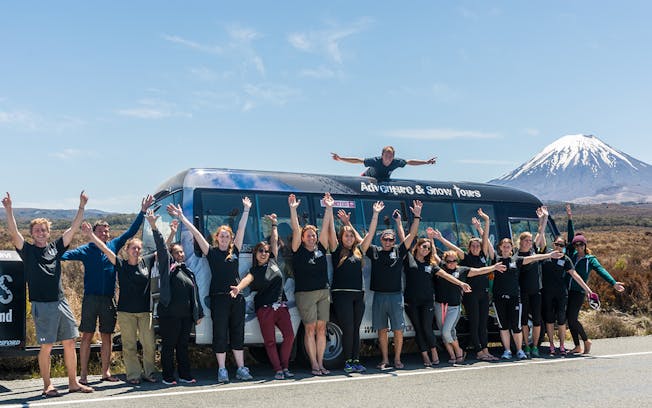 A group of people with their arms raised in joy stand in front of a New ...